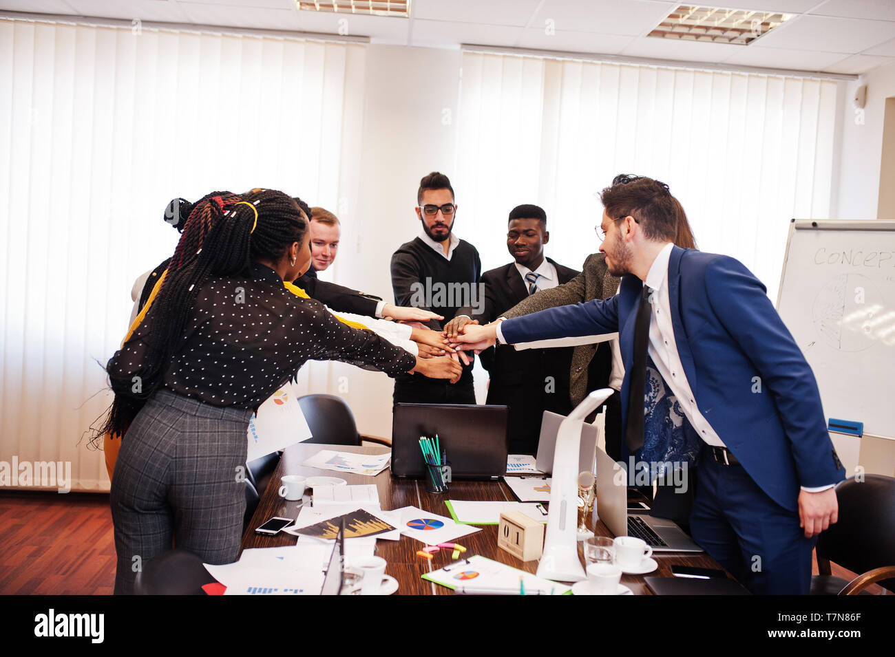 Multiracial business people standing at office and put hands on hands ...