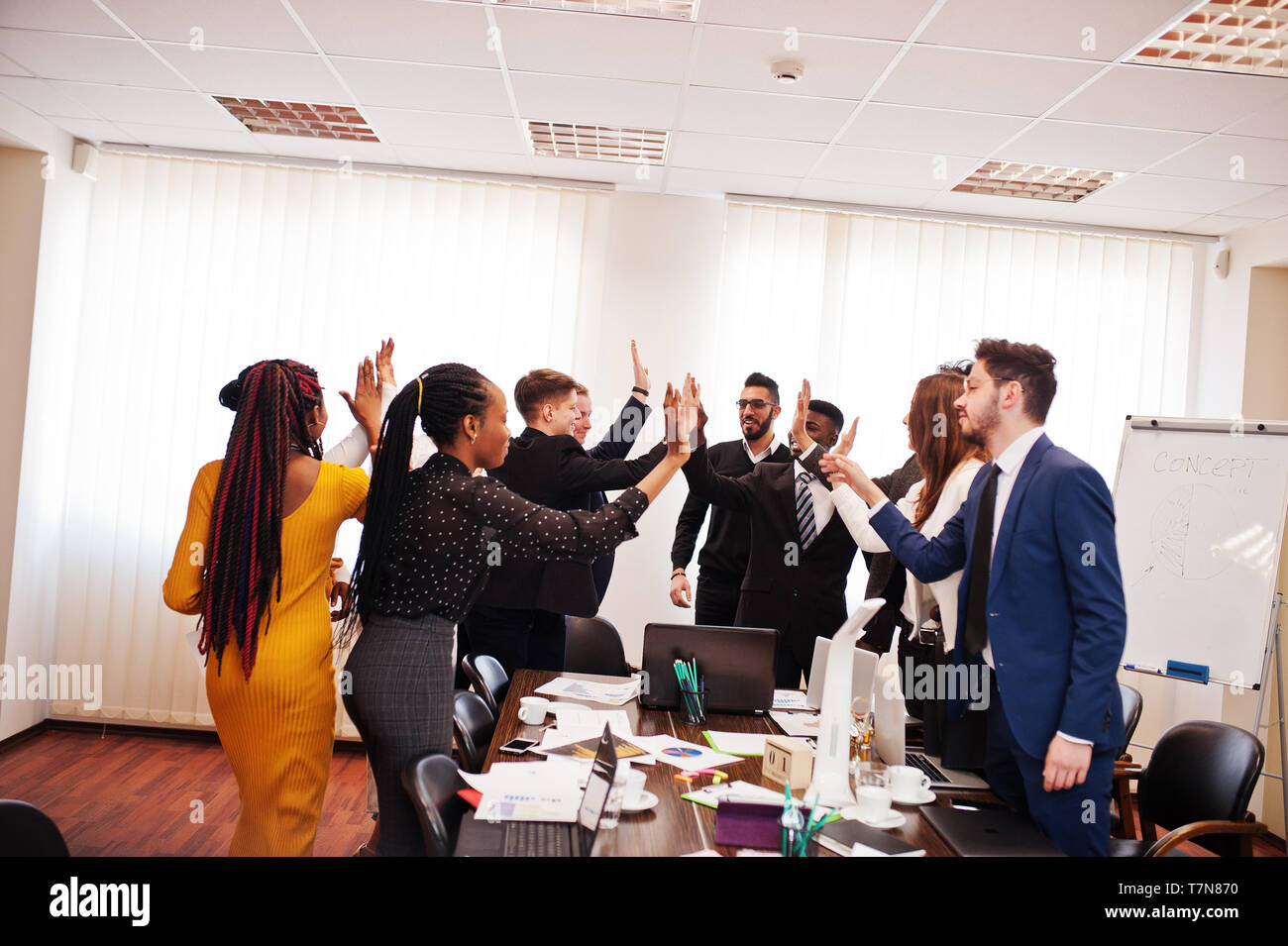 Multiracial business people standing at office and give high five each ...