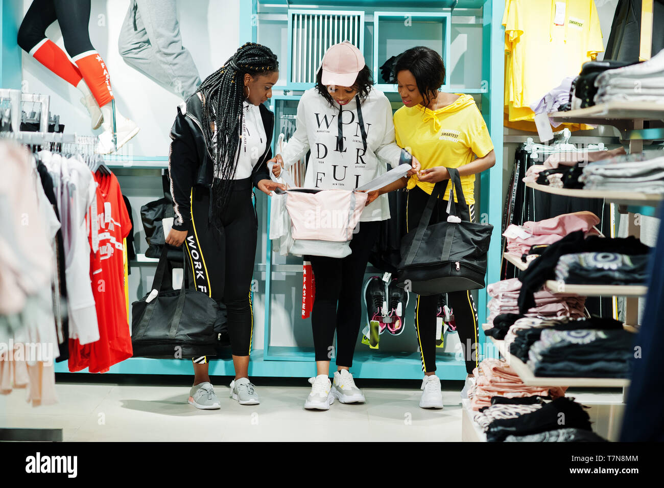 Three afican american women in tracksuits shopping with sport bags at ...