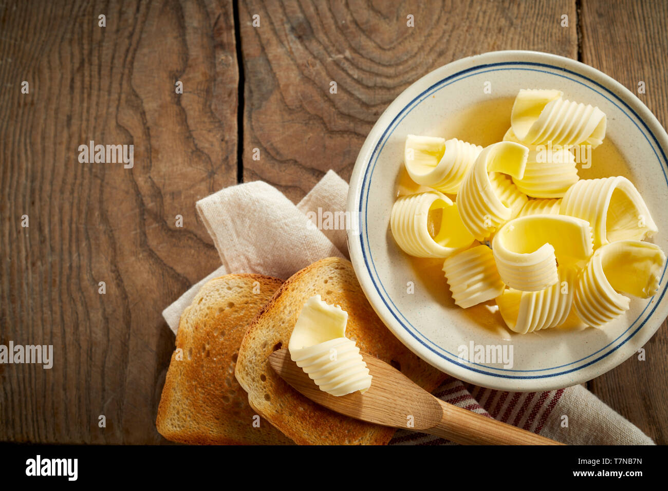 Dish of butter curls with crispy golden toast served on a rustic wood ...