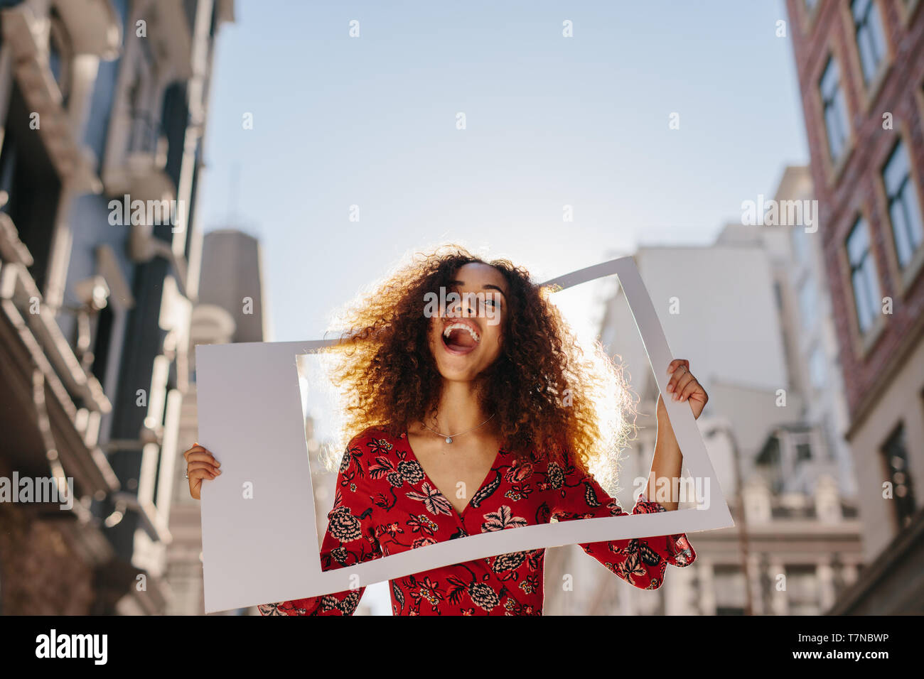 Excited young woman with empty photo frame. Women traveler standing ...