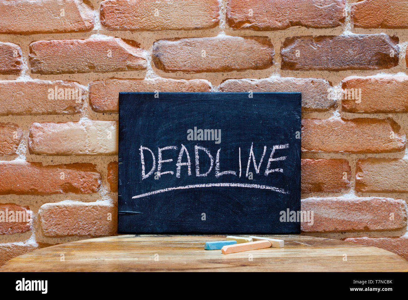 Chalk board with the word "Deadline" drown by hand on wooden table on ...