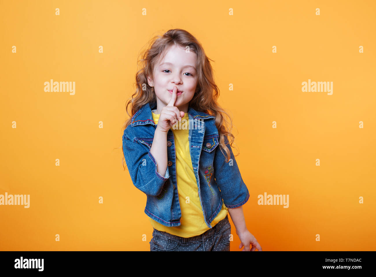 Cute curly girl looking camera and making silence gesture isolated over ...