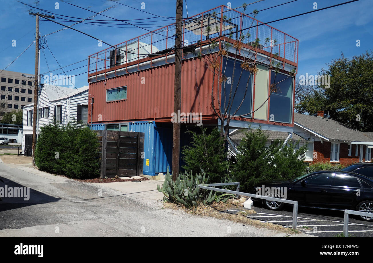 Next to old mid-century wooden home a recycled shipping container rises ...