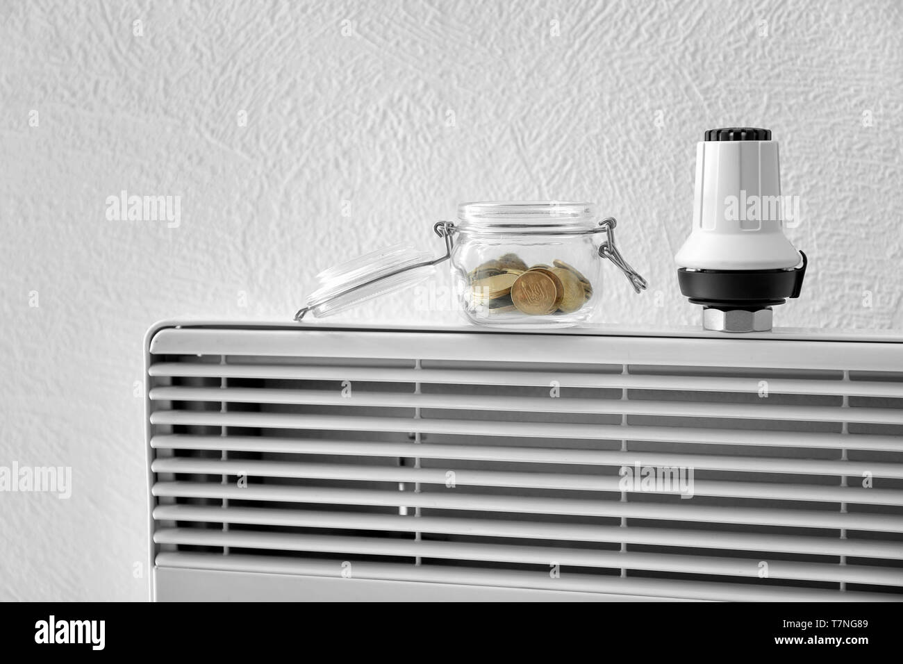 Jar with coins and thermostat on calorifer at home. Heating saving ...