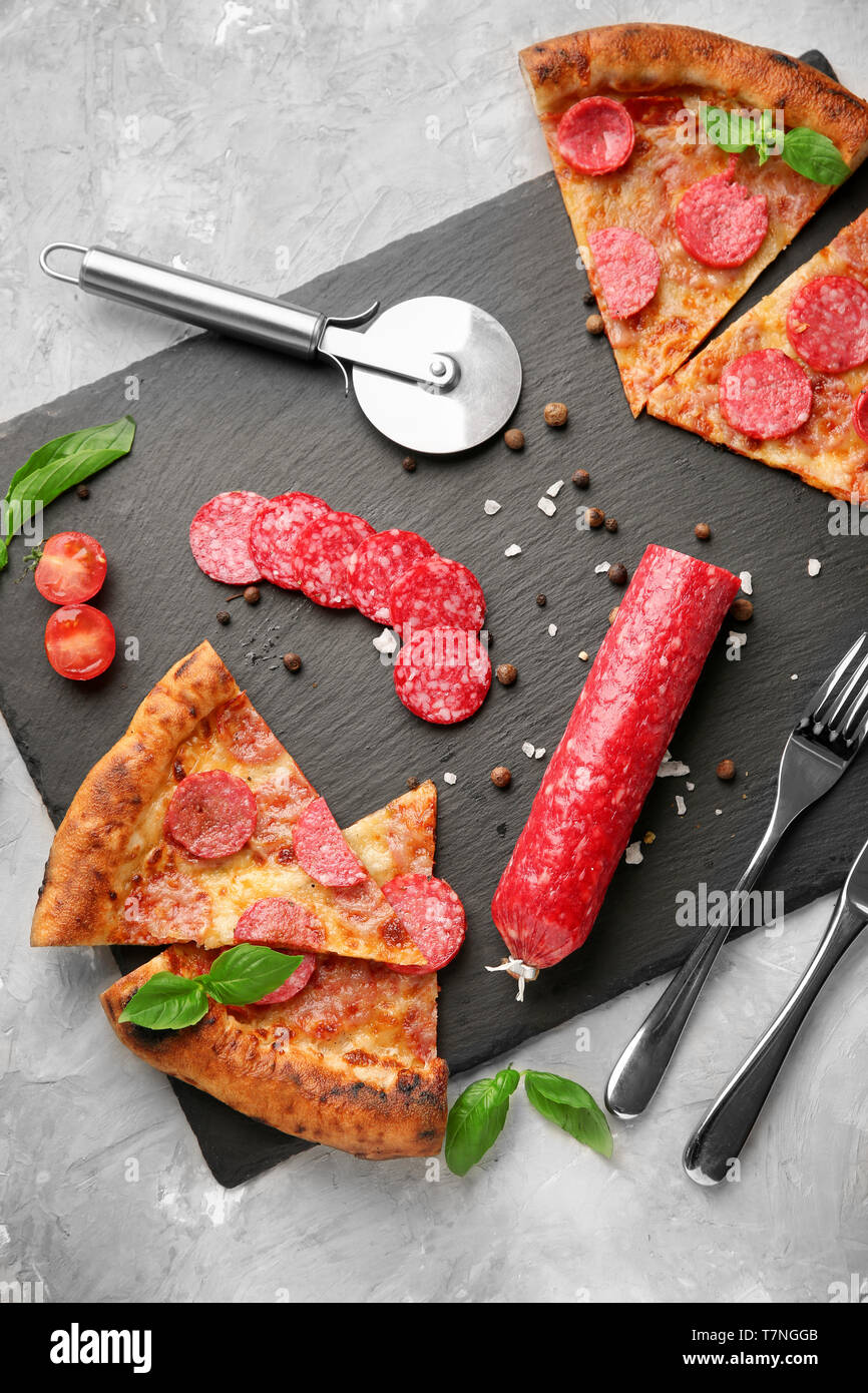 Slate plate with slices of delicious pizza on table Stock Photo - Alamy