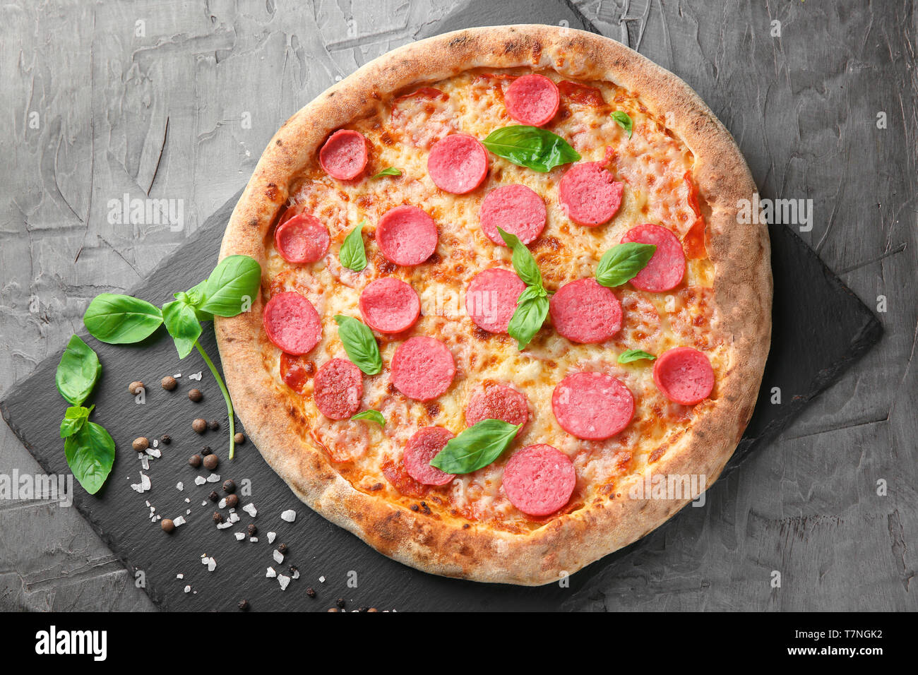 Slate plate with delicious pizza on table Stock Photo - Alamy