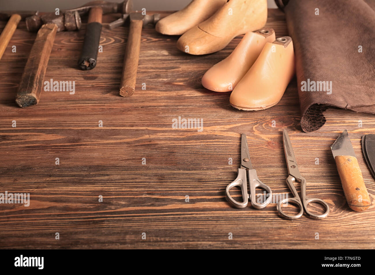 Shoe-trees with craft tools on wooden table in leather workshop Stock ...