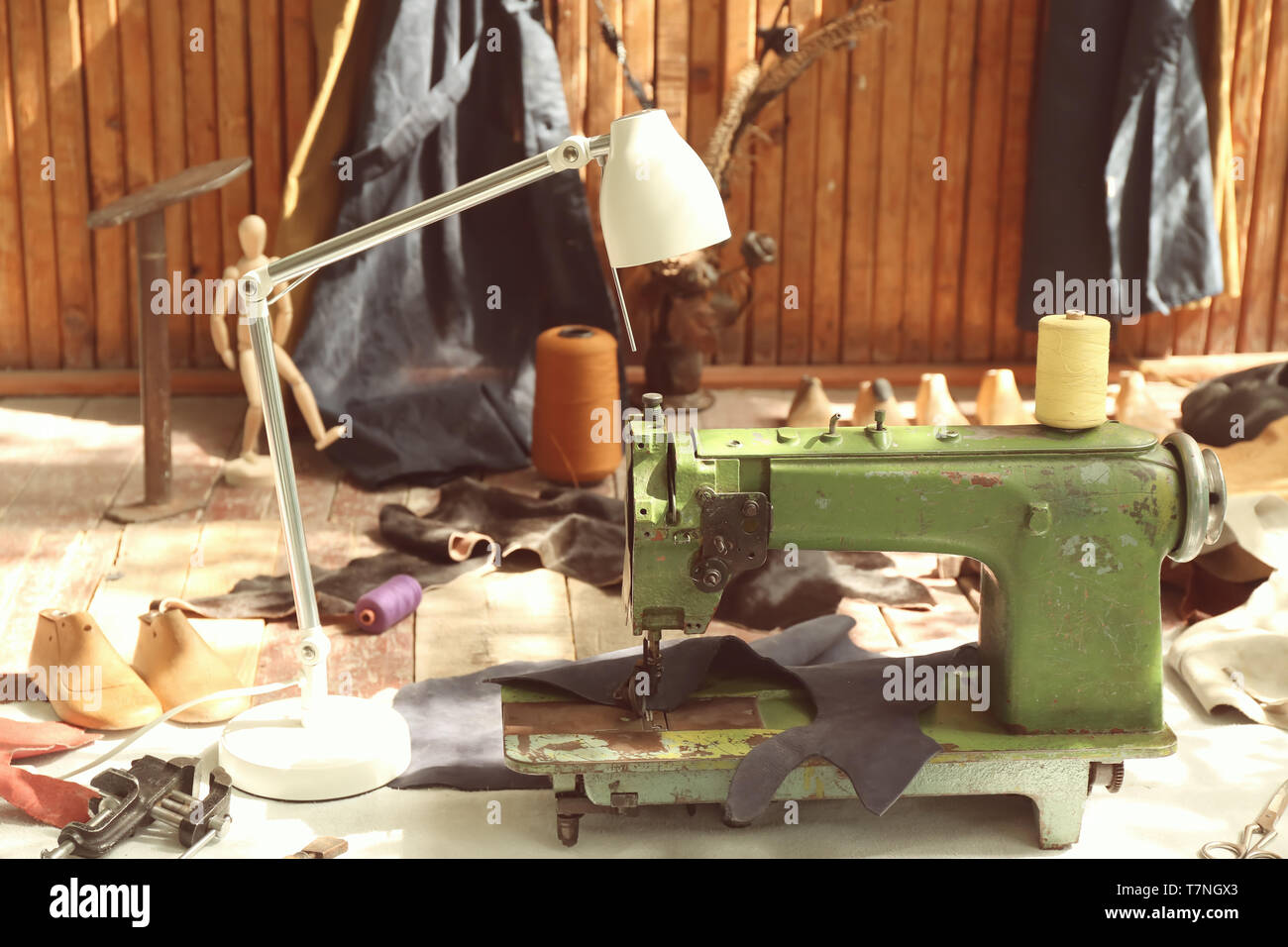 Old sewing machine with leather and craft items on floor in workshop ...