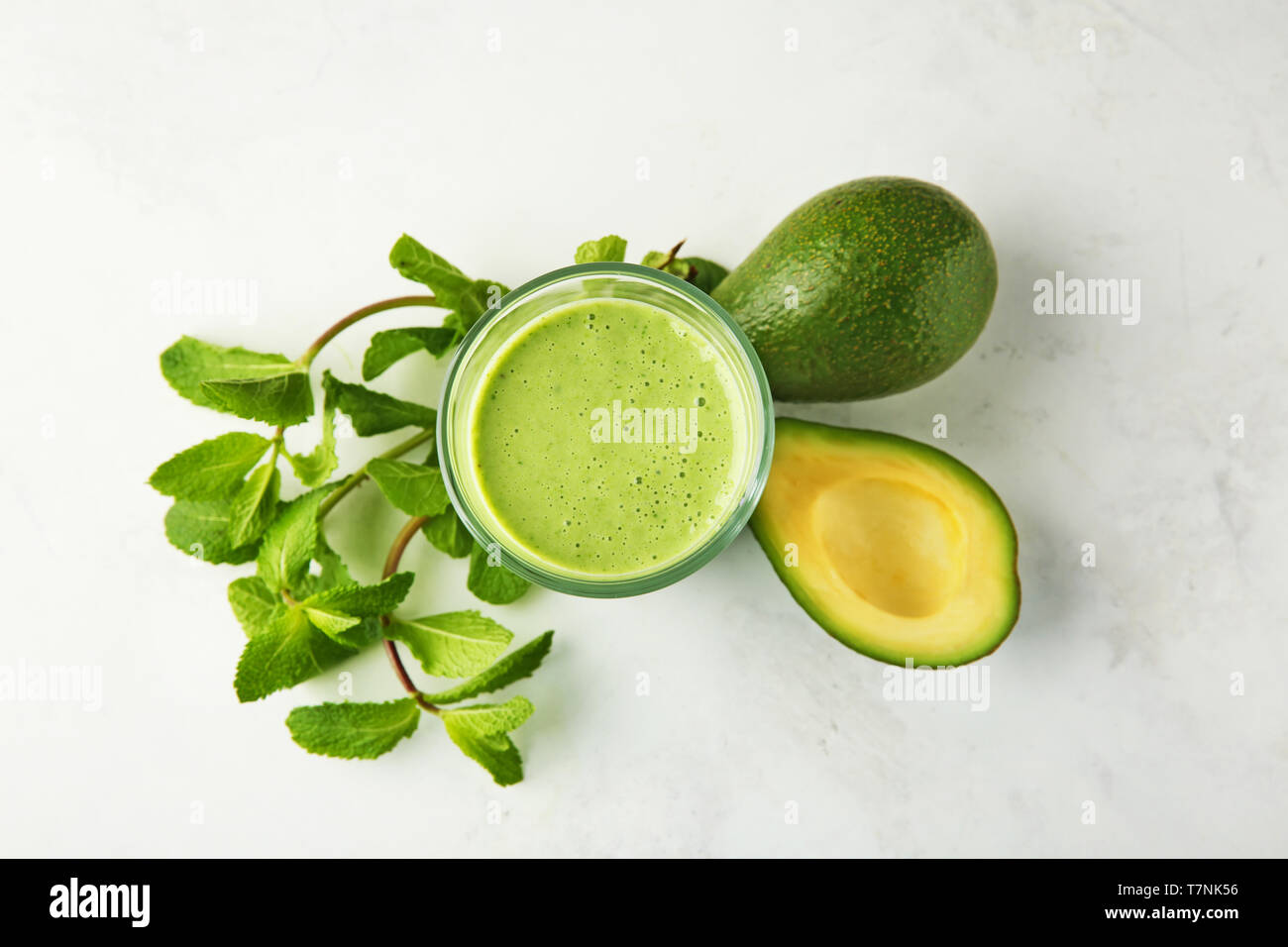 Ripe avocados, mint and glass of tasty smoothie on light background ...