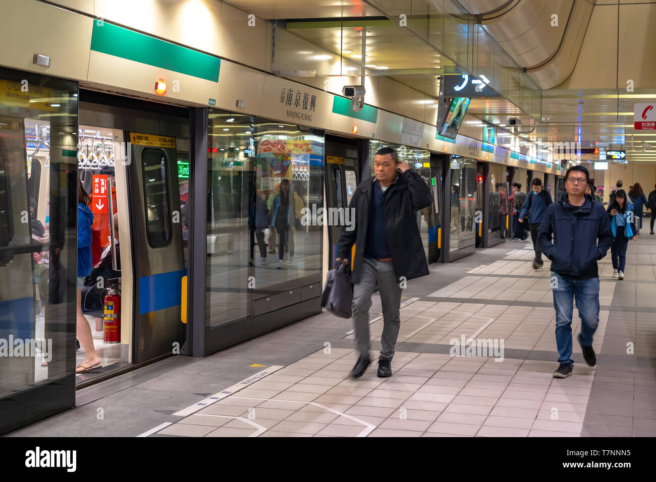 Taipei metro station hall and platform. Subway passengers walk through ...