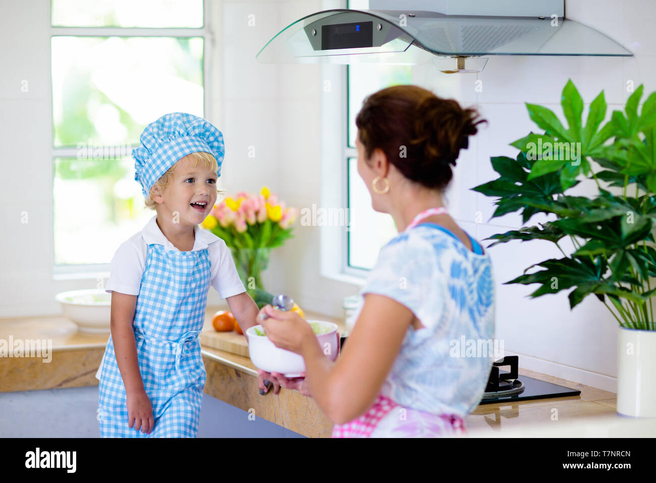 Mother and kid cook in white kitchen. Mom and child cooking at home ...