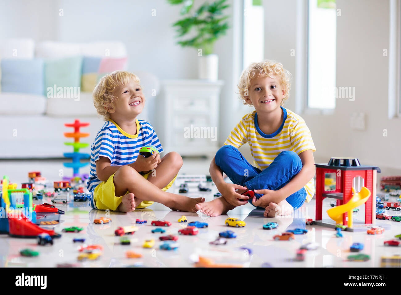 Kids play with toy cars in white room. Little boy playing with car and ...