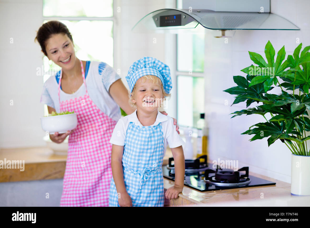 Mother and kid cook in white kitchen. Mom and child cooking at home ...