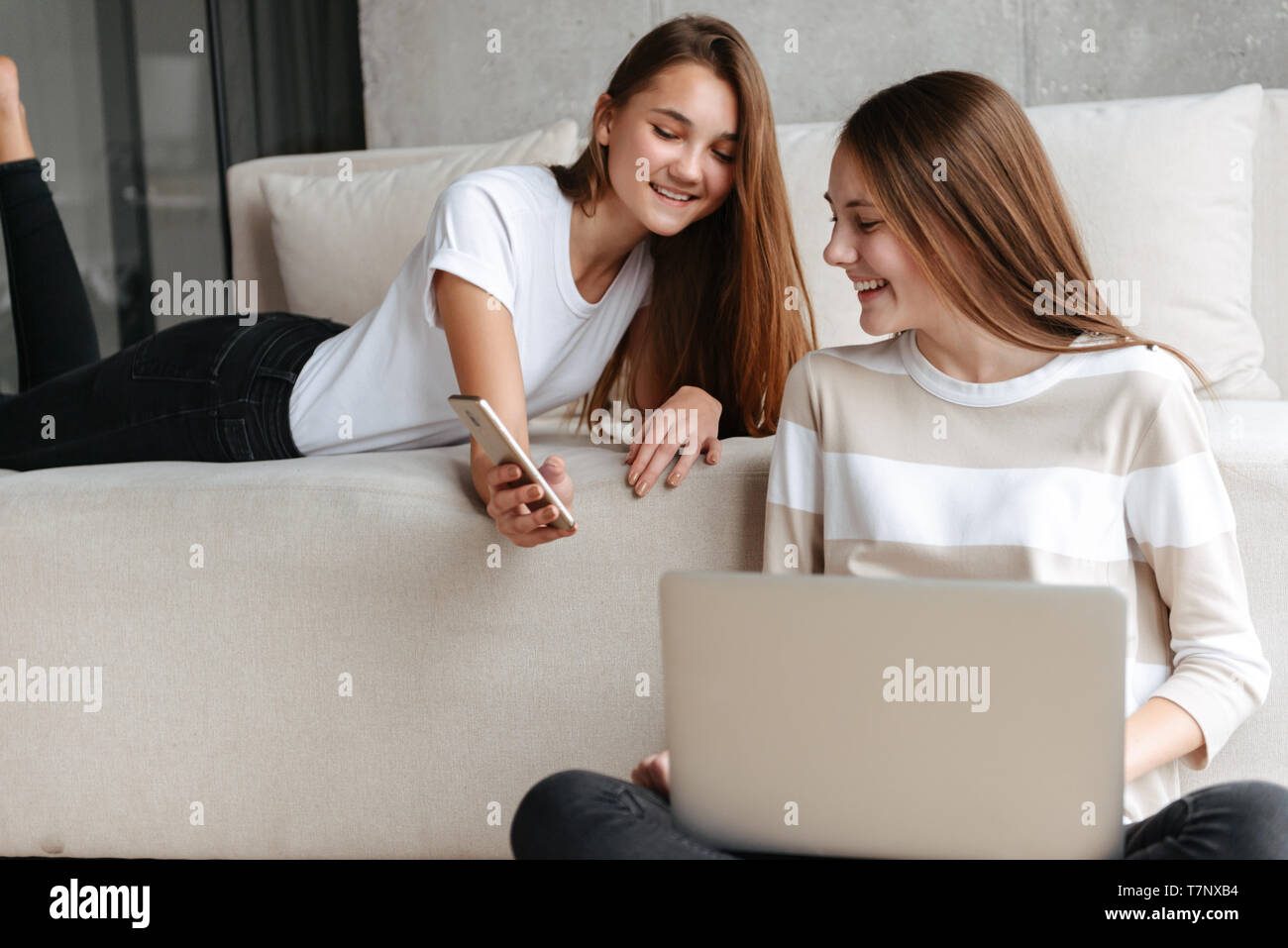 Two lovely cheerful young teenage girls using laptop computer while ...