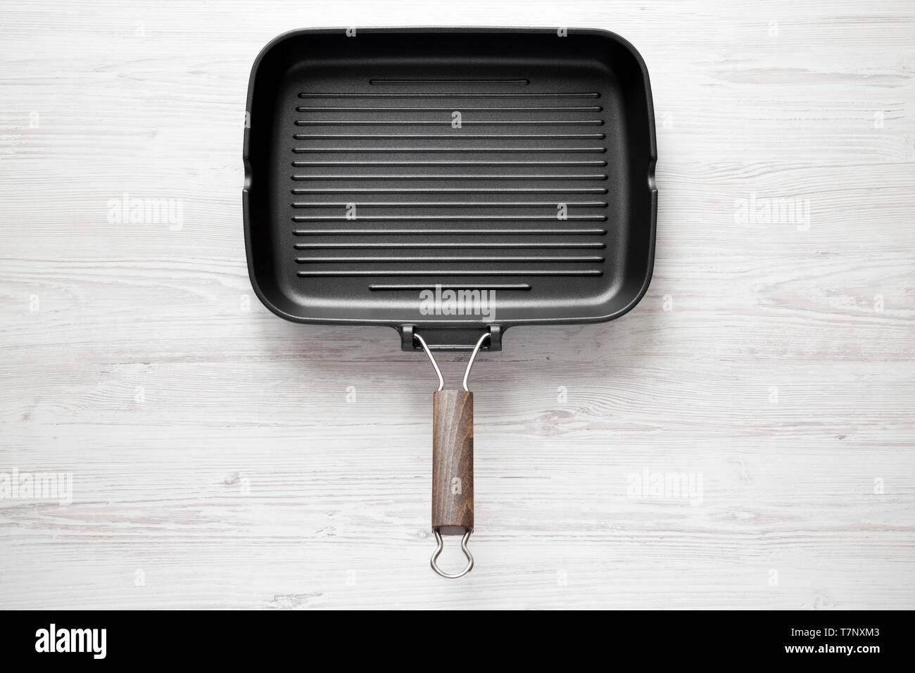 Empty grill pan on a white wooden table, top view. Overhead, from above ...