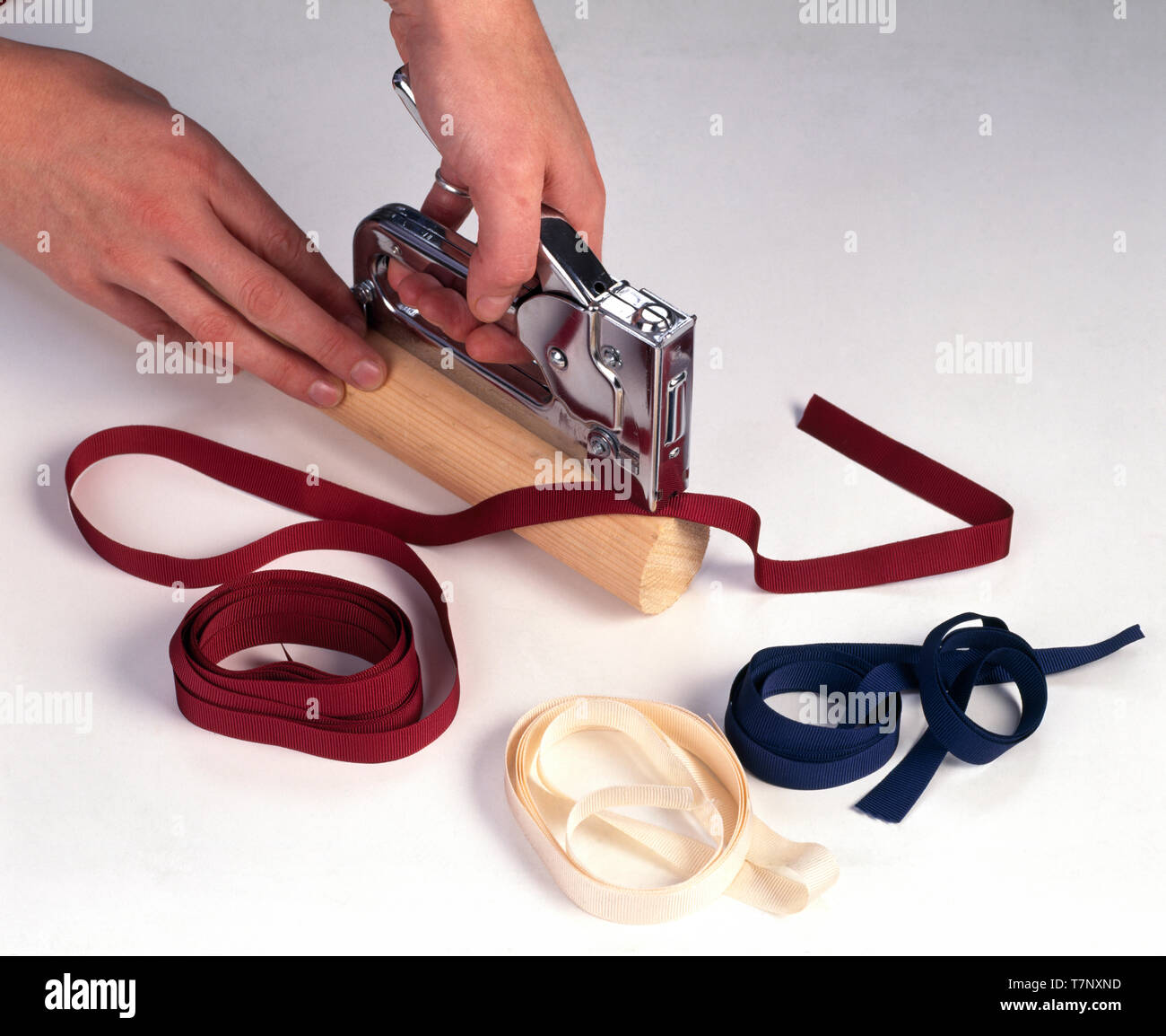 Hand using stapler to attach ribbon to pole Stock Photo - Alamy