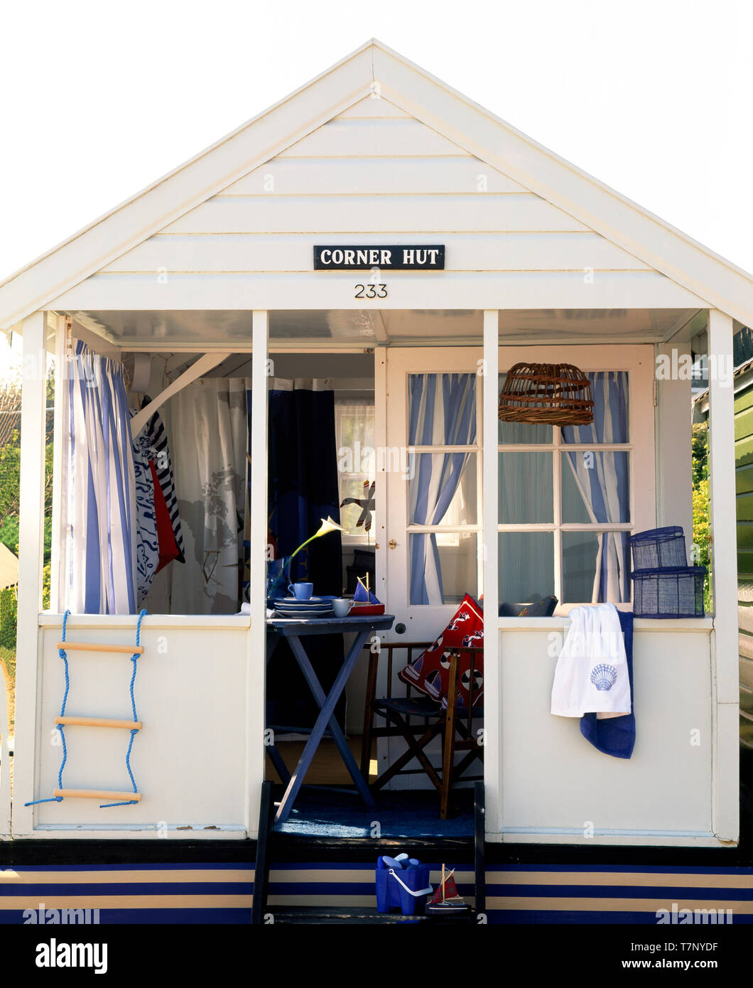 Table and chair on veranda of white beach hut Stock Photo - Alamy