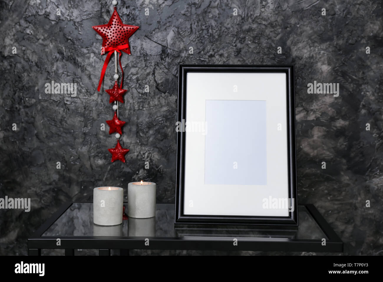 Photo frame with candles on table against dark textured background ...