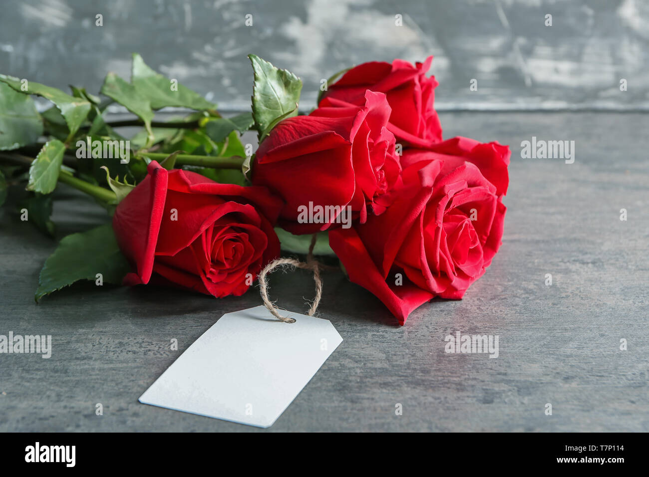 Beautiful roses with tag on grey background Stock Photo - Alamy