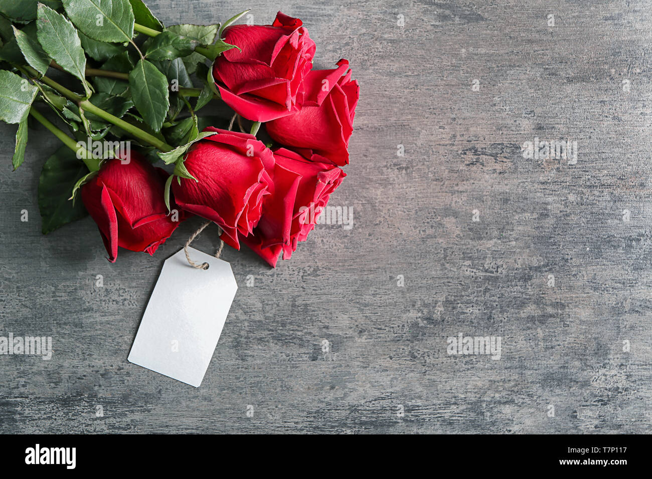 Beautiful roses with tag on grey background Stock Photo - Alamy