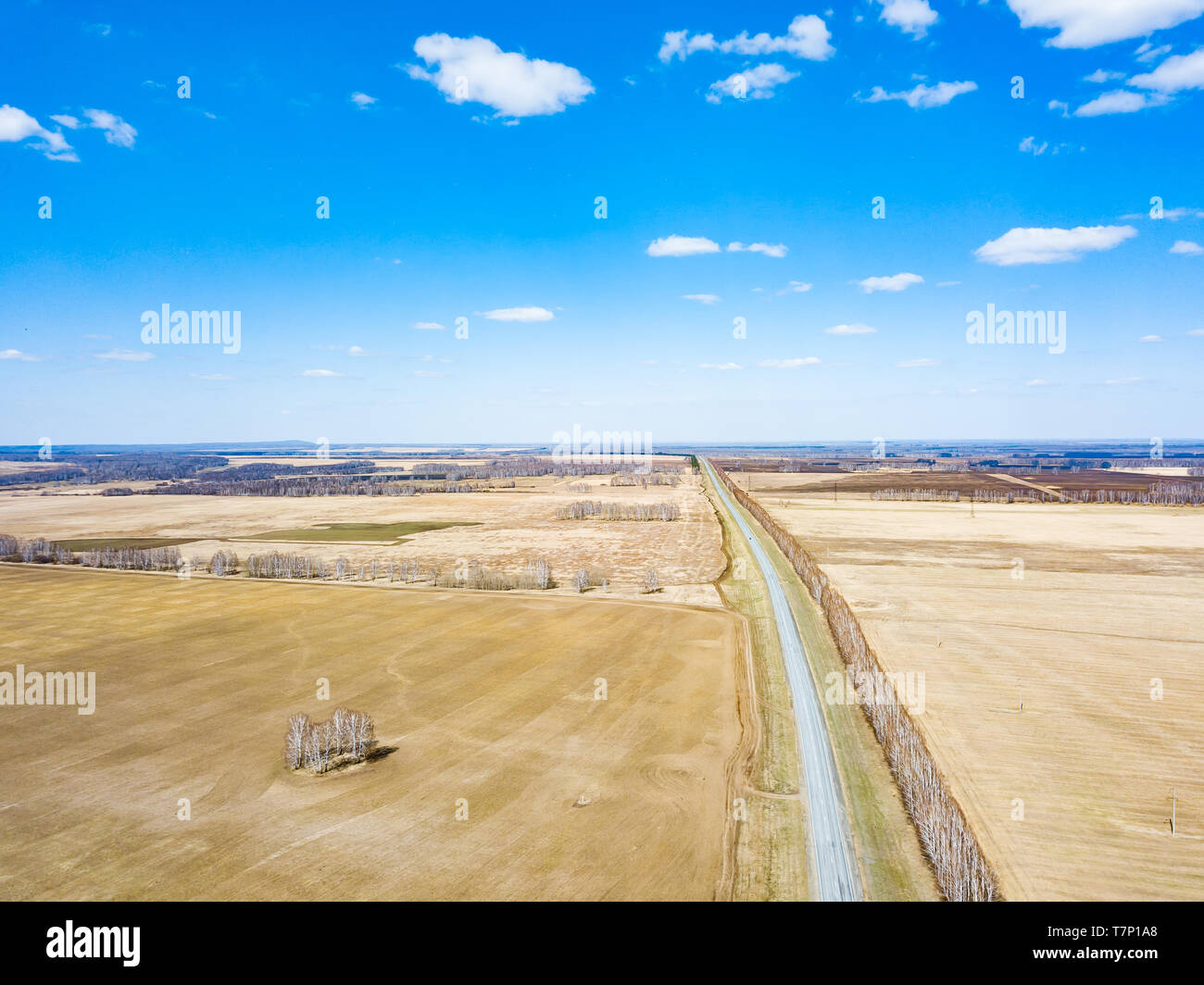 Aerial view of the asphalt road in a field with yellow grass during ...