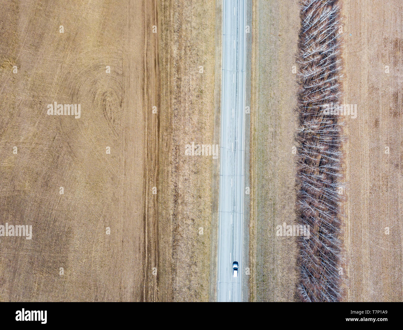 Aerial view of the asphalt road in a field with yellow grass during ...