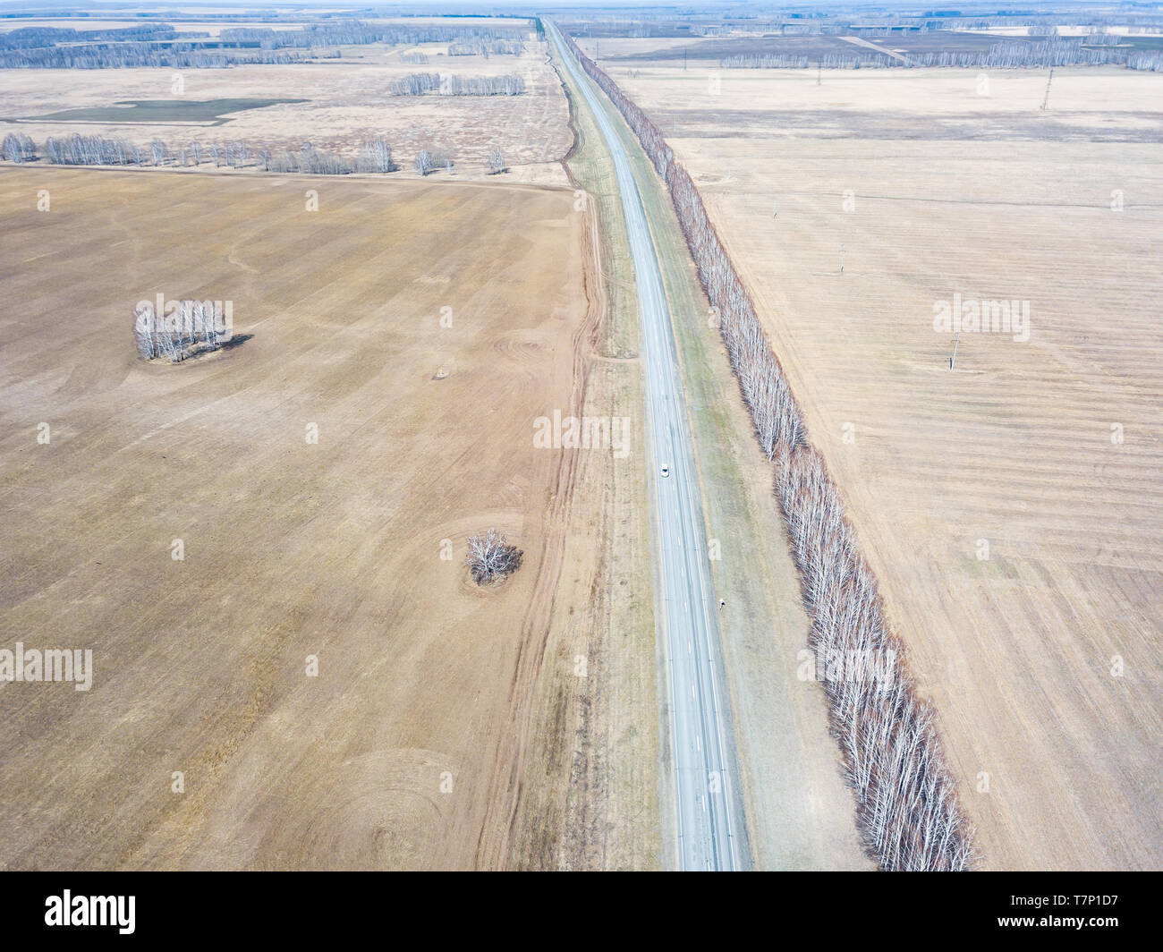 Aerial view of the asphalt road in a field with yellow grass during ...