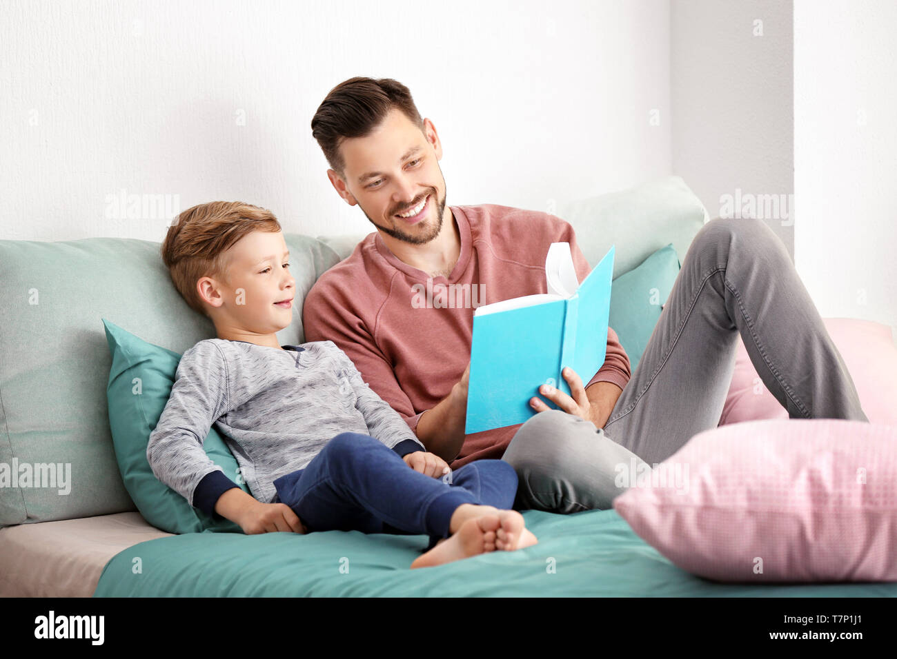 Father and his son reading book together at home Stock Photo - Alamy