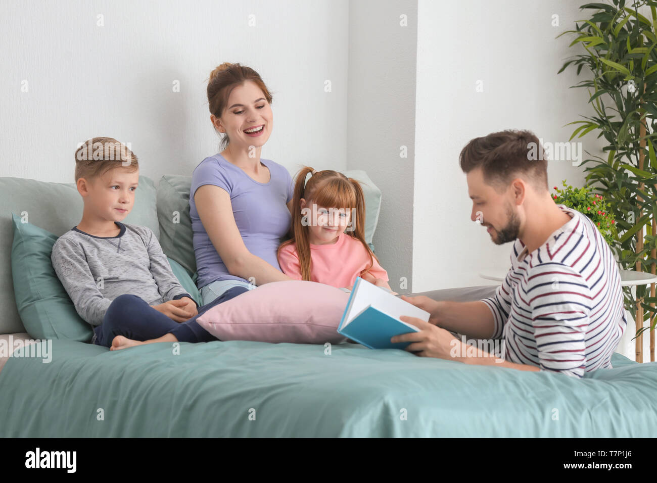 Happy family reading book together at home Stock Photo - Alamy