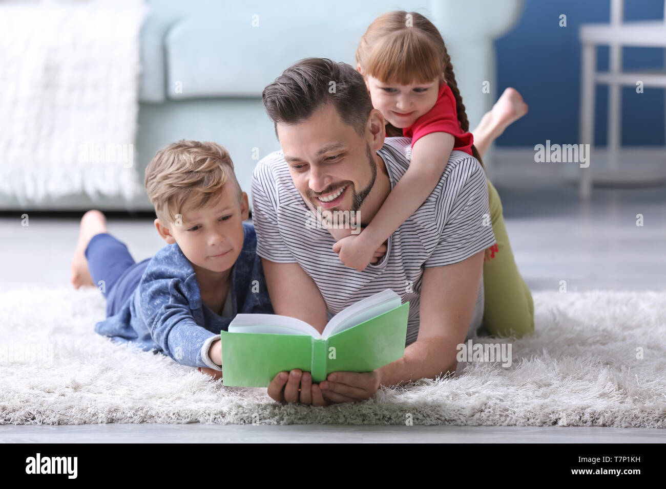 Father and his children reading book together at home Stock Photo - Alamy