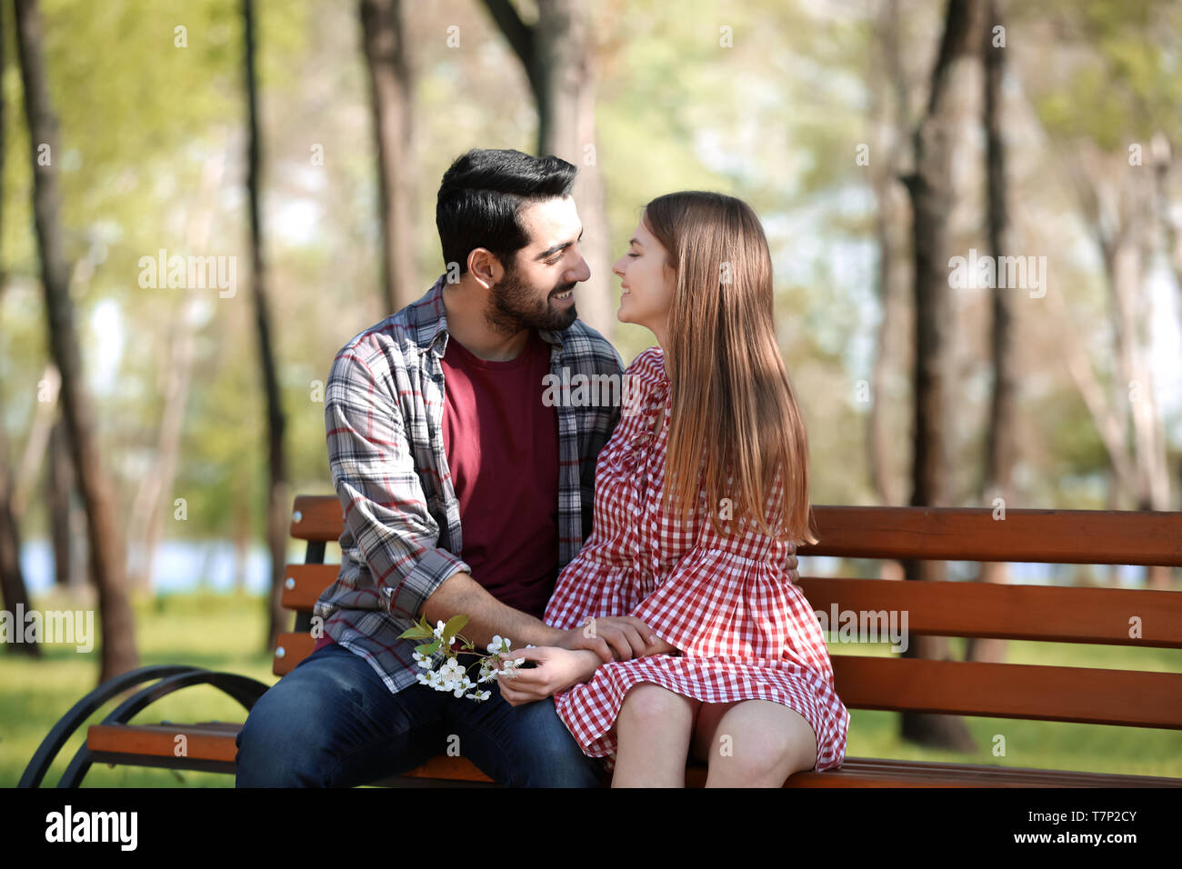 Happy young couple resting on bench in park Stock Photo - Alamy