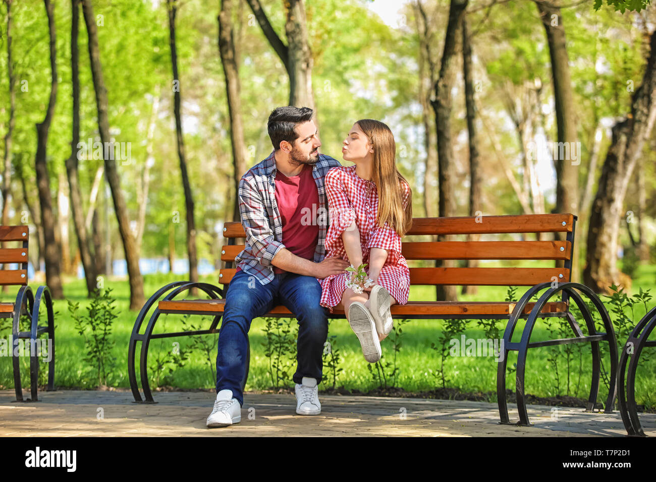 Happy young couple resting on bench in park Stock Photo - Alamy