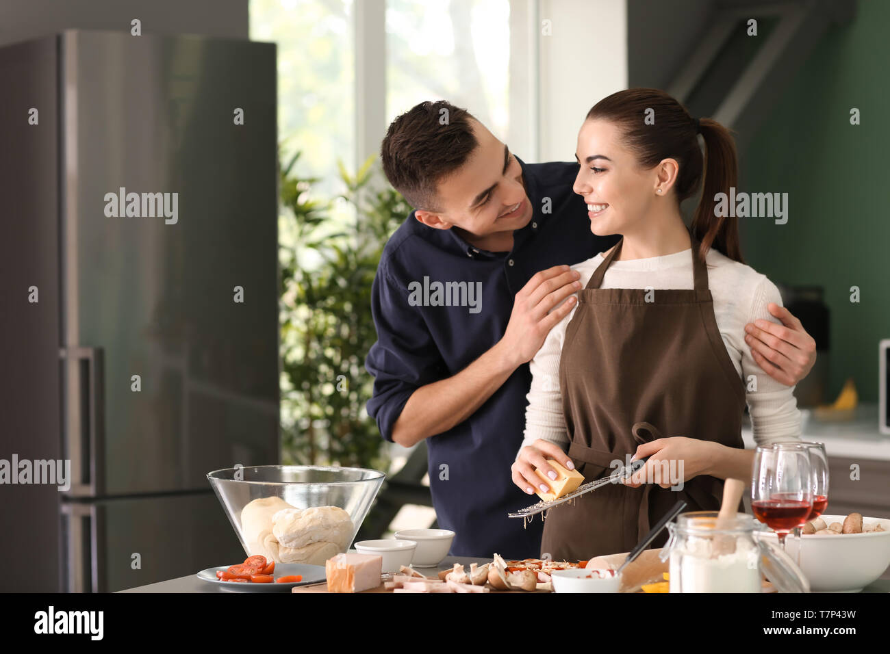 Young woman cooking with boyfriend in kitchen Stock Photo - Alamy