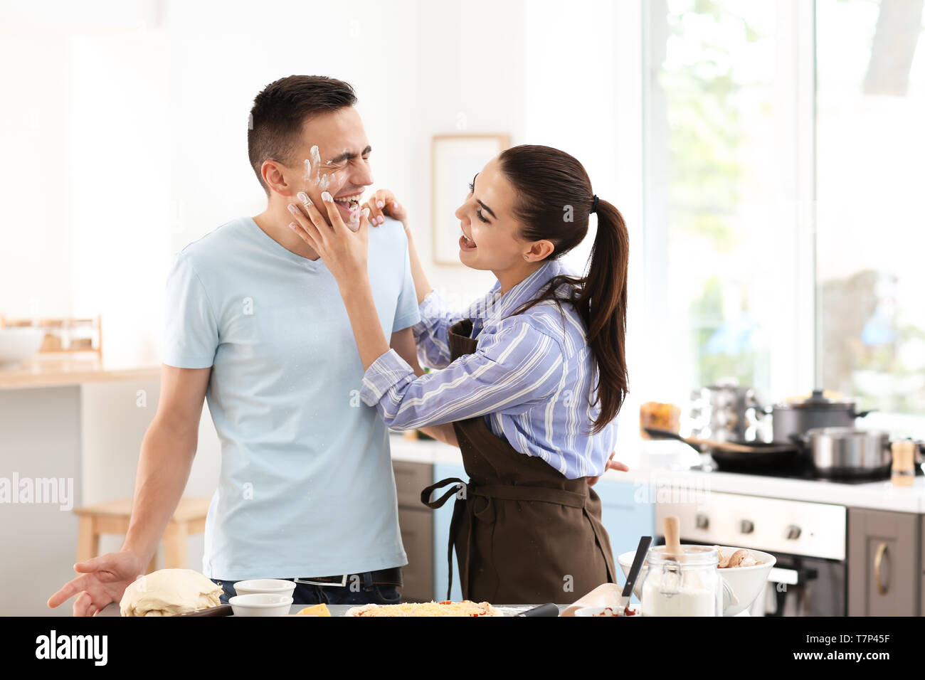 Young couple having fun while cooking in kitchen Stock Photo - Alamy