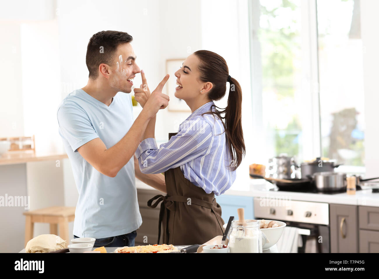 Young couple having fun while cooking in kitchen Stock Photo - Alamy