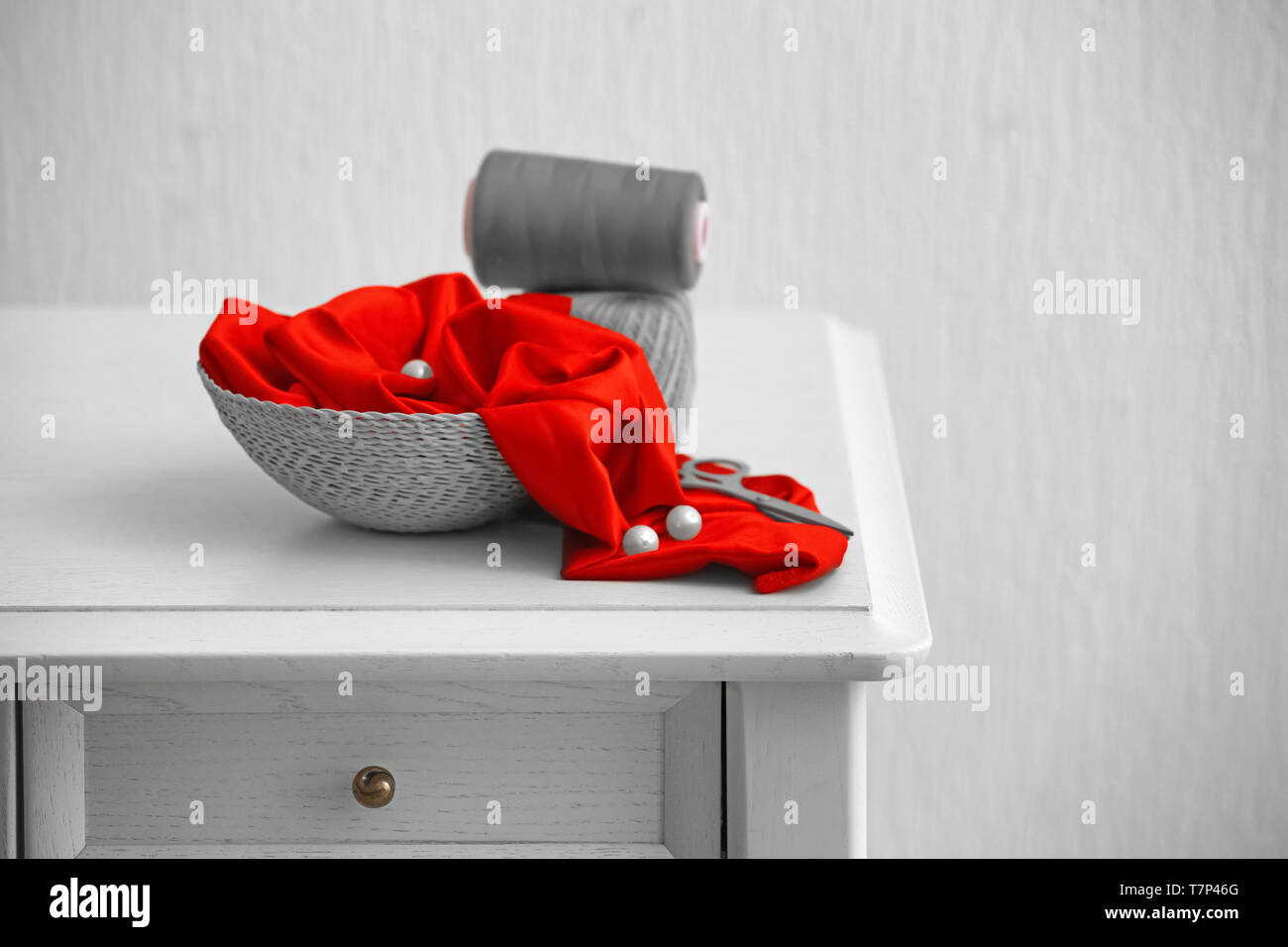 Basket with color fabric and sewing accessories on table against light ...