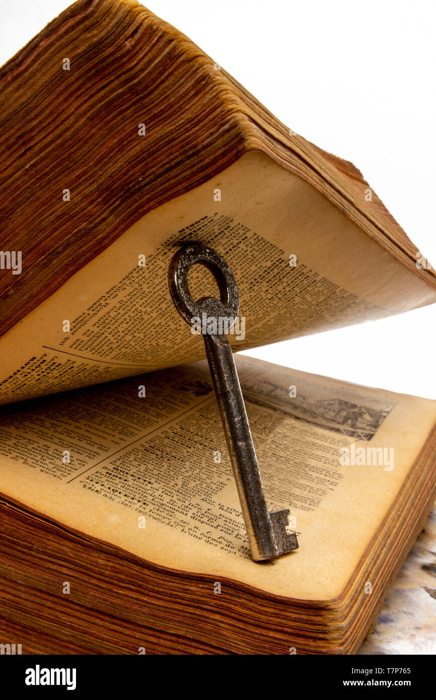 Vertical closeup of a key in the middle of the pages of an old book ...