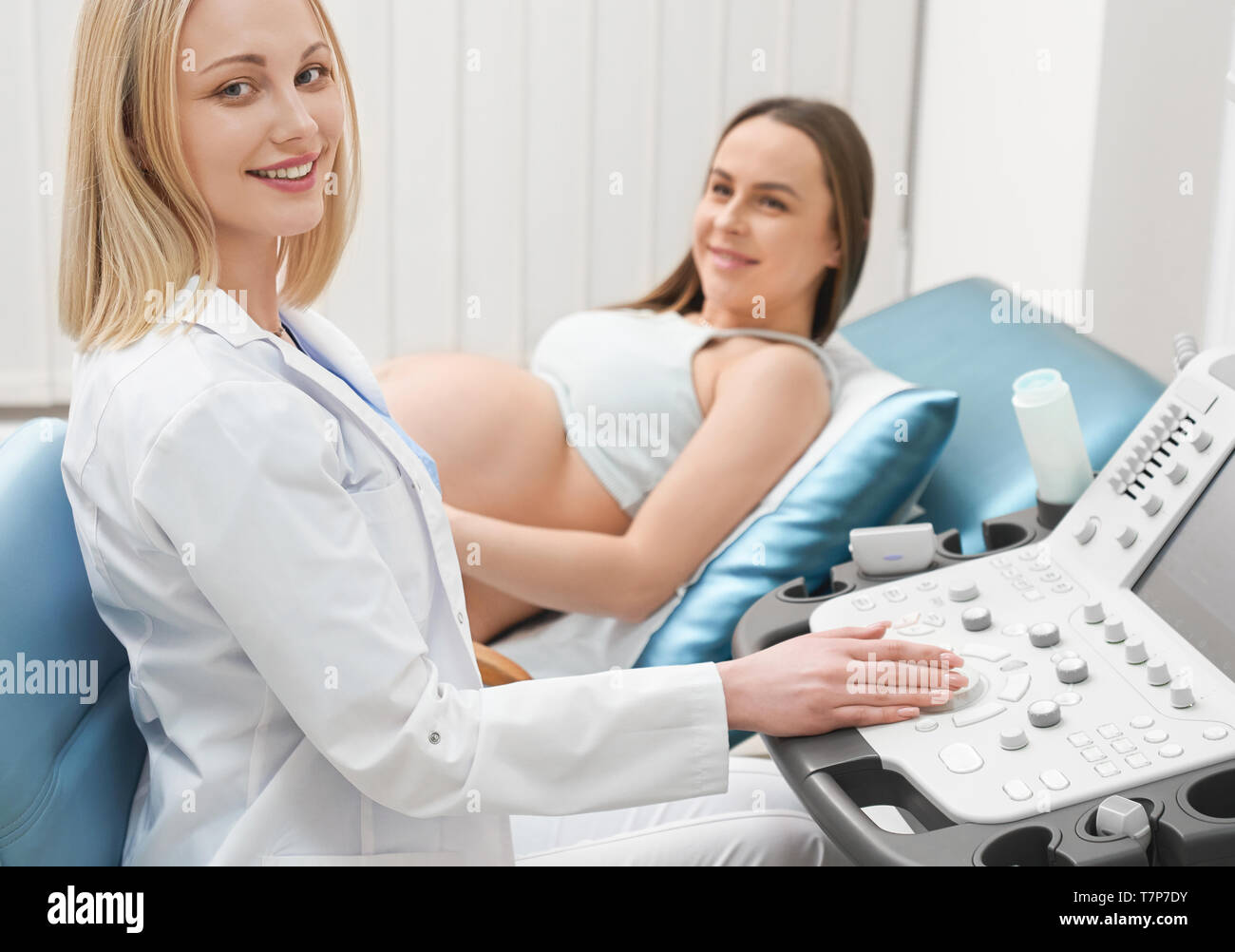 View from side of pretty female doctor looking at camera and smiling ...