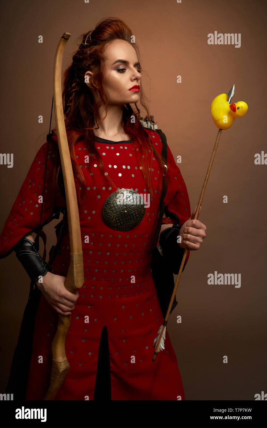 Female fighter in red armor keeping dow and rubber duck and posing on ...