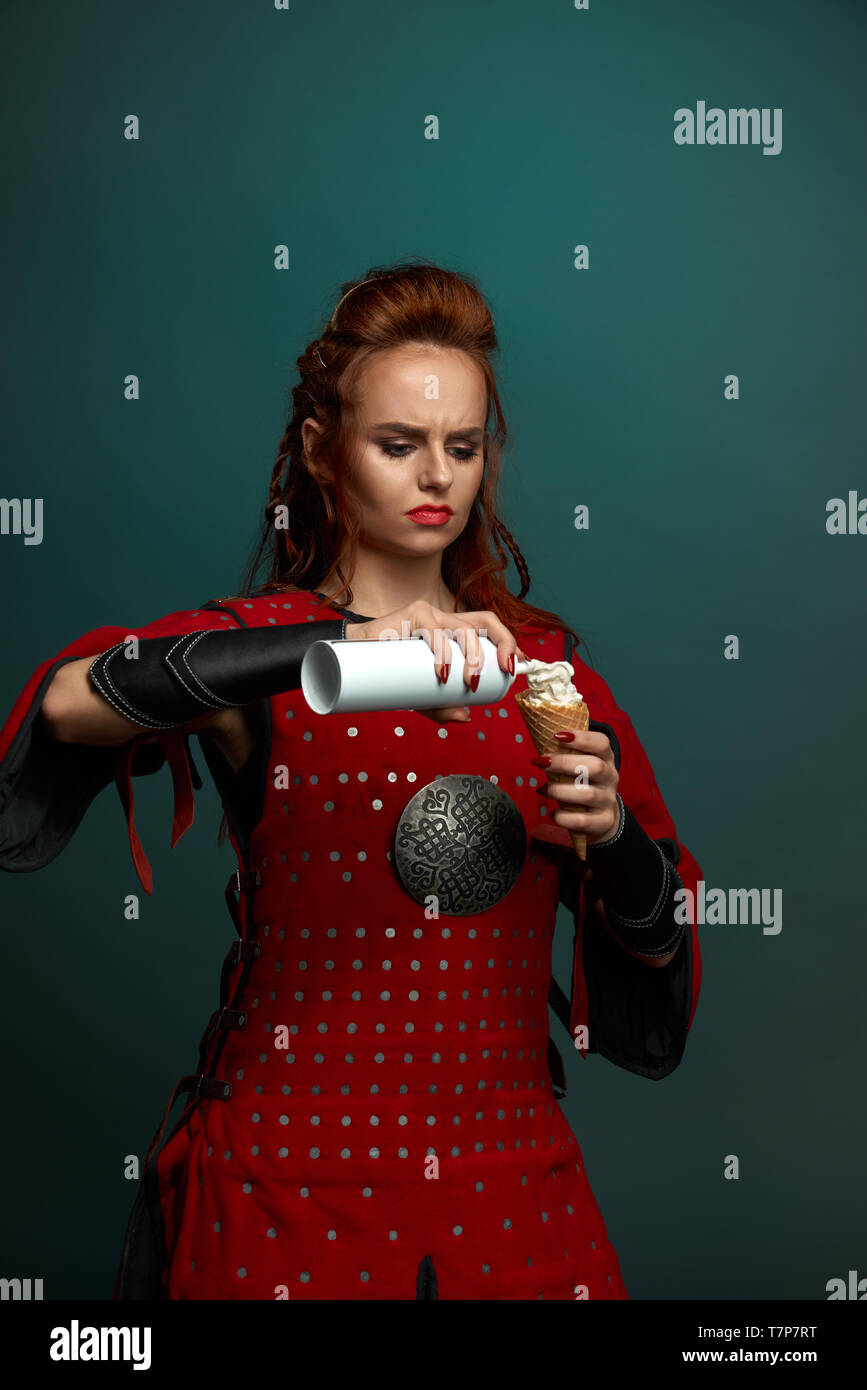 Front view of funny red haired female warrior eating delicious ice ...