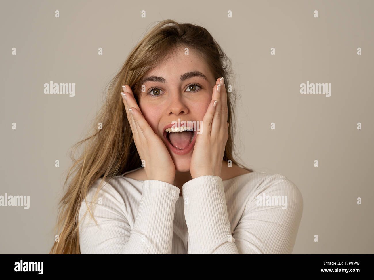 Beautiful young blonde teenager woman with happy face making surprised ...