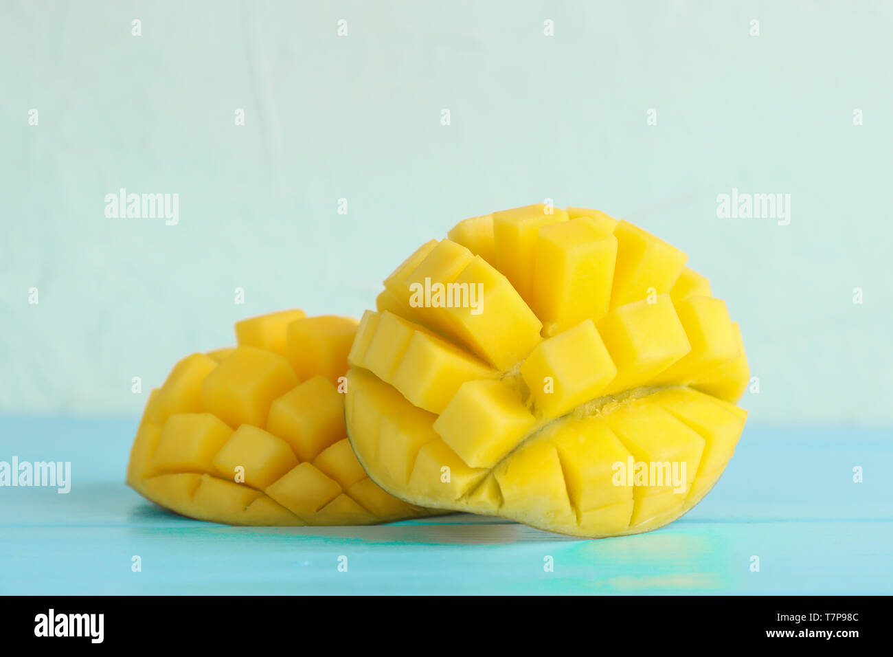 Cut ripe mangoes on color table against white background, closeup Stock ...