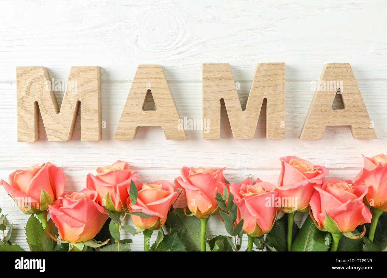 Beautiful orange roses and inscription Mom on white background, space ...