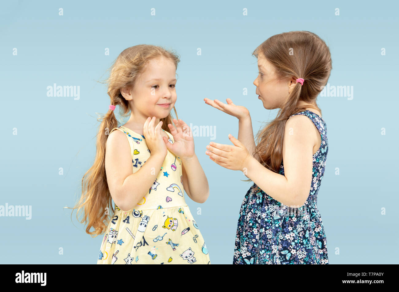 Beautiful emotional little girls isolated on blue background. Half ...