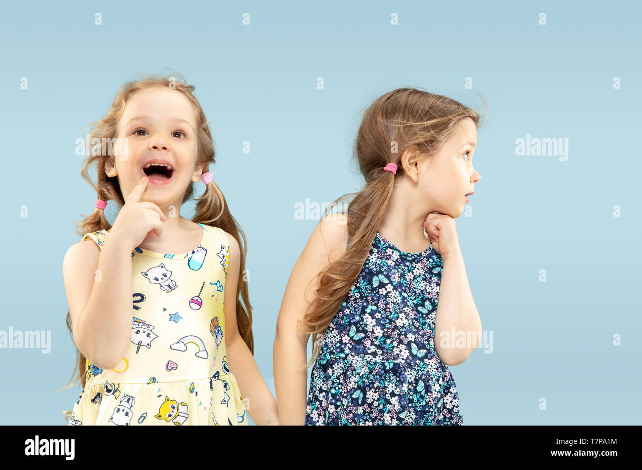 Beautiful emotional little girls isolated on blue background. Half ...