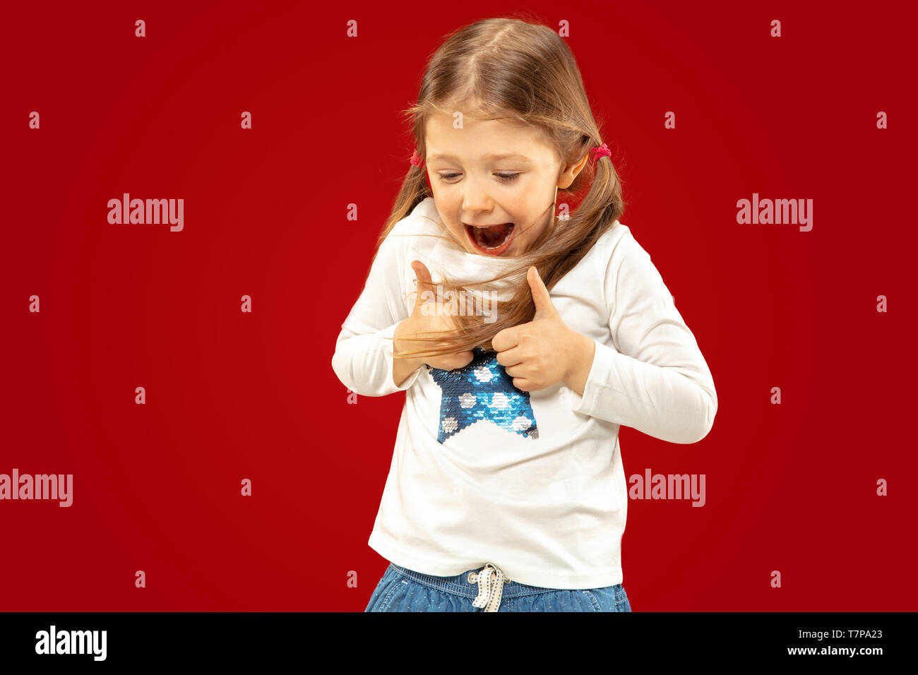 Beautiful emotional little girl isolated on red background. Half-lenght ...