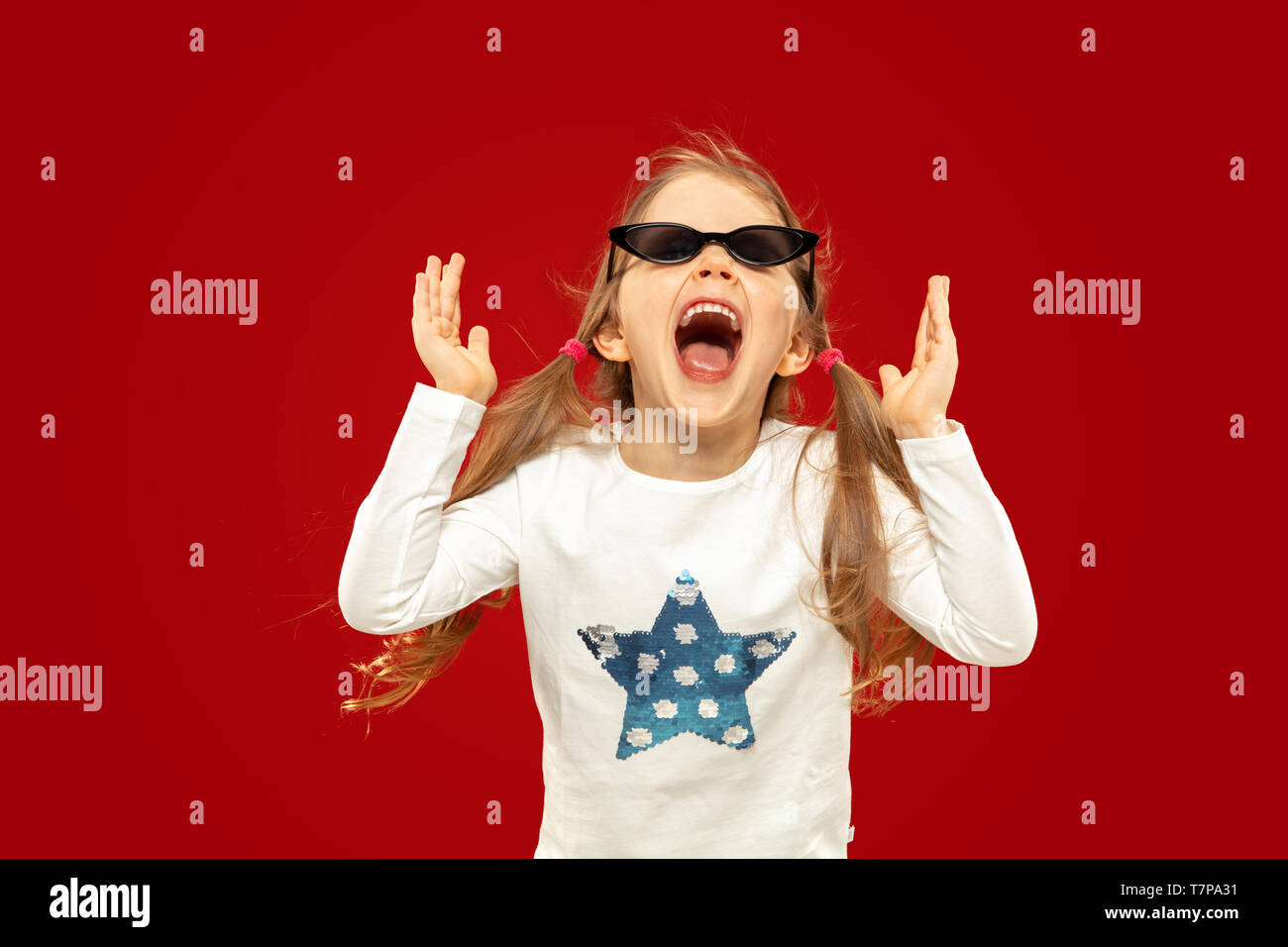 Beautiful emotional little girl isolated on red background. Half-lenght ...