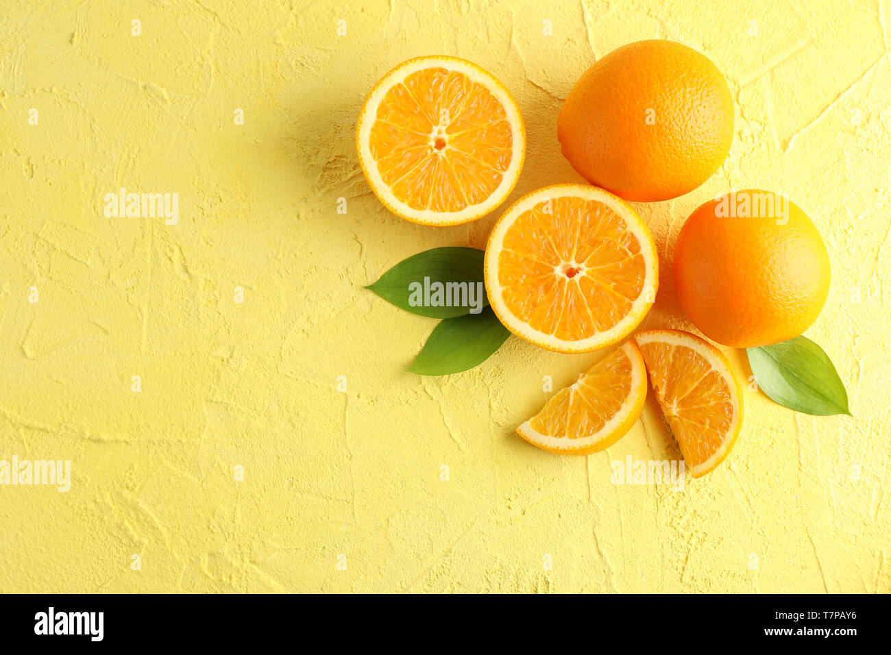 Flat lay composition with ripe oranges and leaves on color background ...