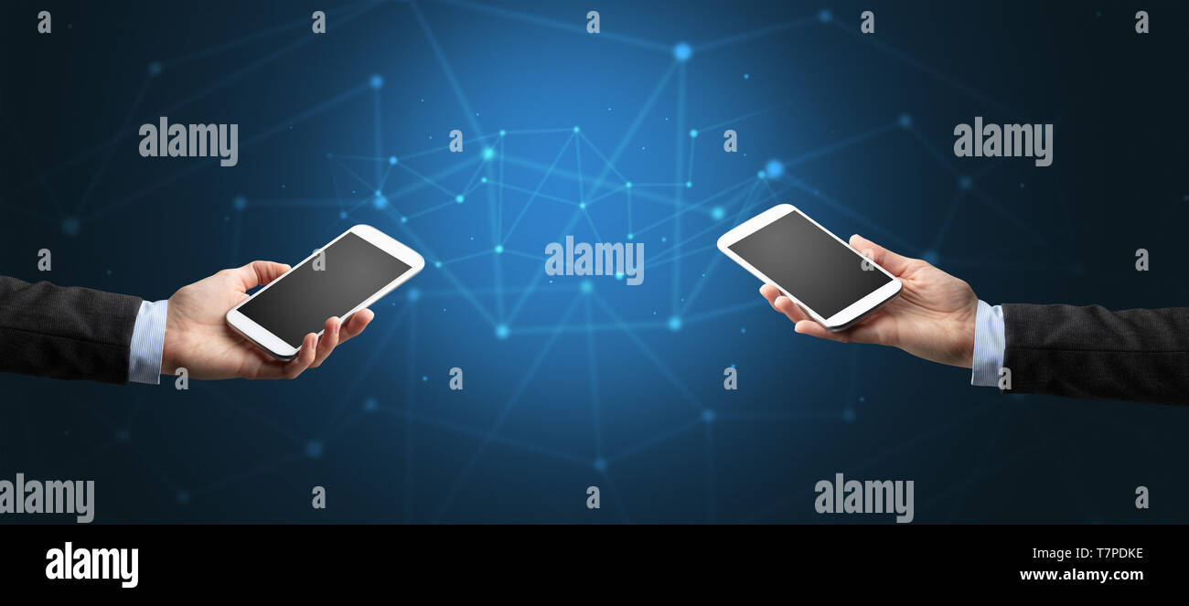 Close up of two hands holding smartphones to each other, wireless ...